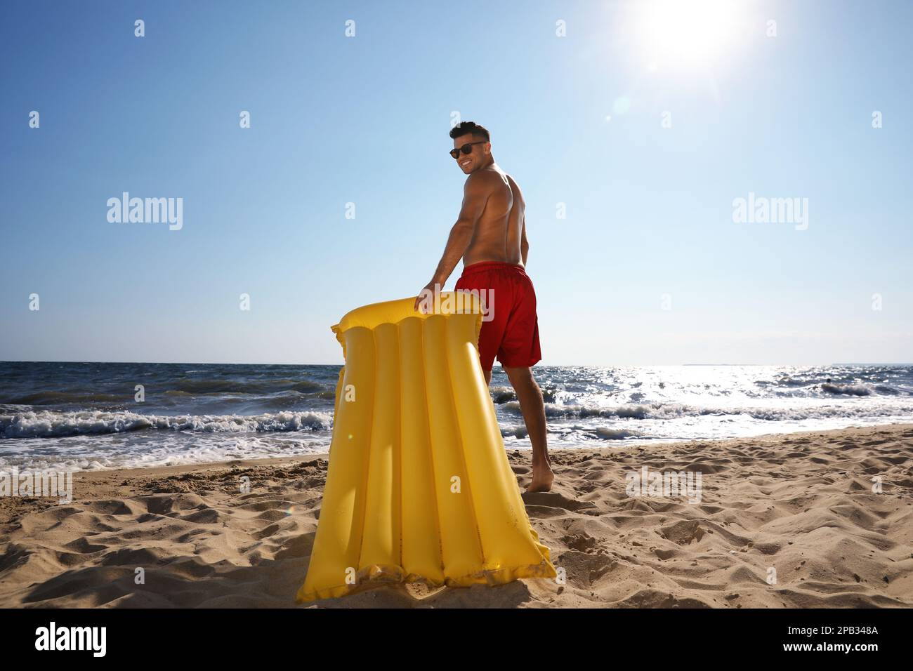 Man with yellow inflatable mattress at beach Stock Photo - Alamy