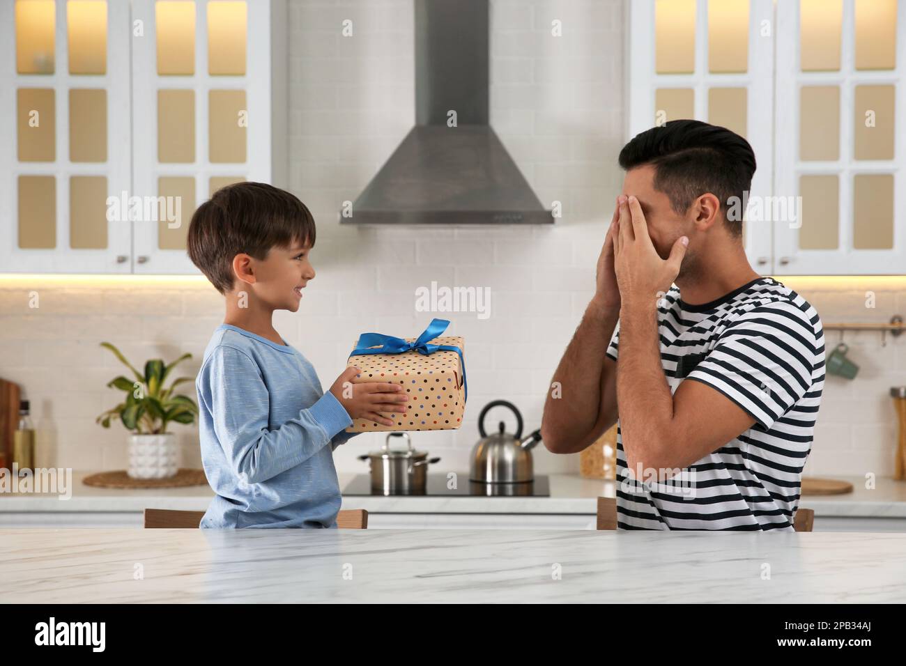Man receiving gift for Father's Day from his son in kitchen Stock Photo ...