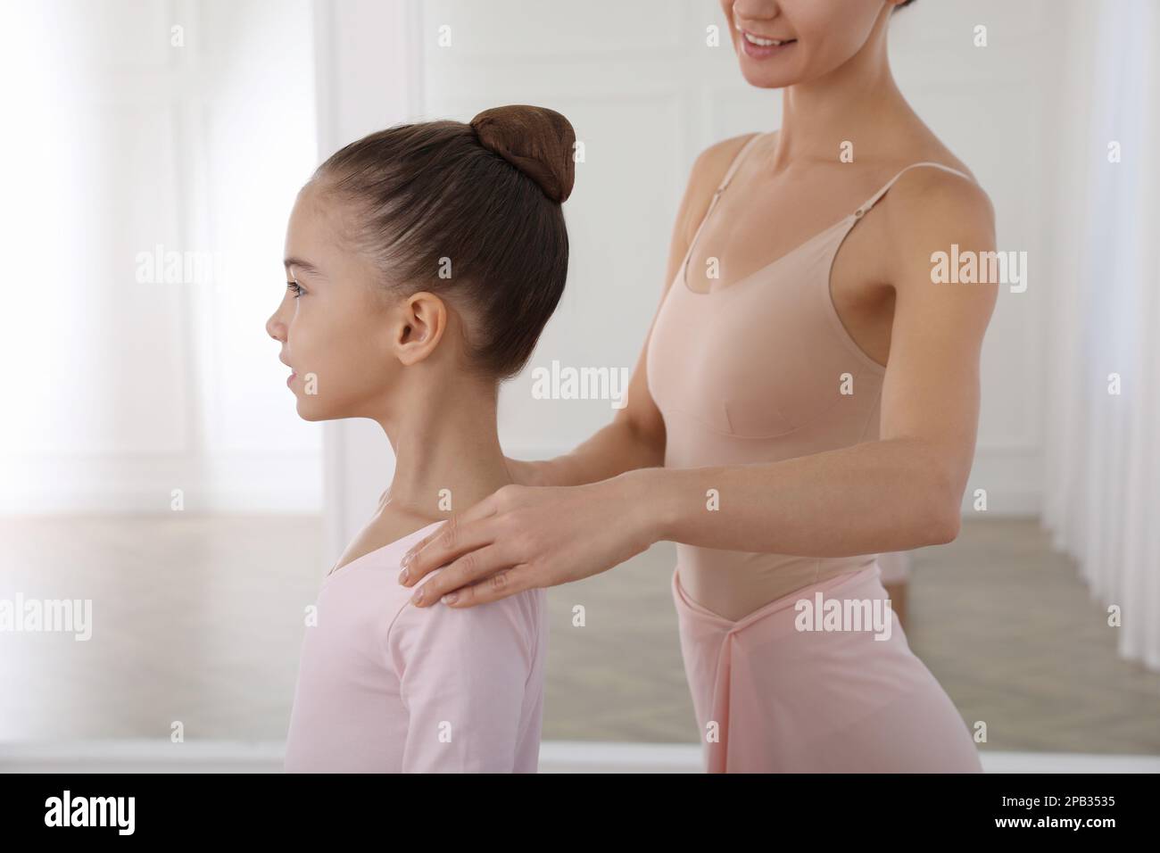 Ballet teacher fixing little girl's posture in studio Stock Photo - Alamy