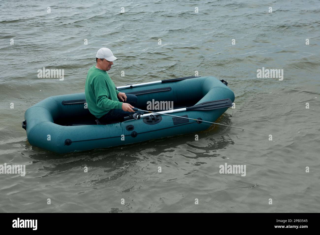 Man fishing with rod from inflatable rubber boat on river Stock Photo ...