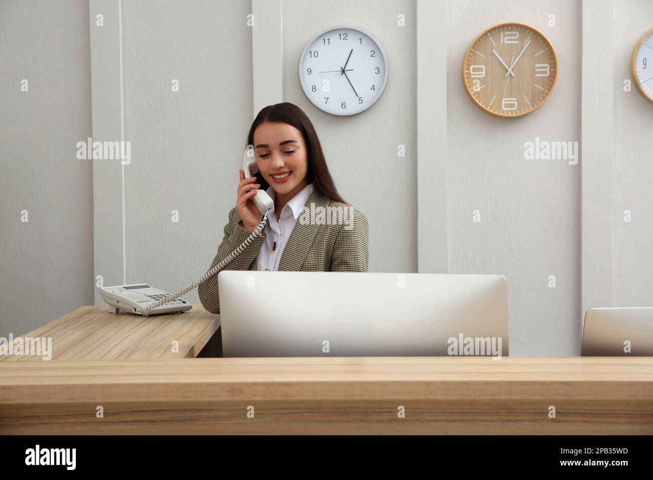 Beautiful receptionist talking on phone at counter in hotel Stock Photo ...