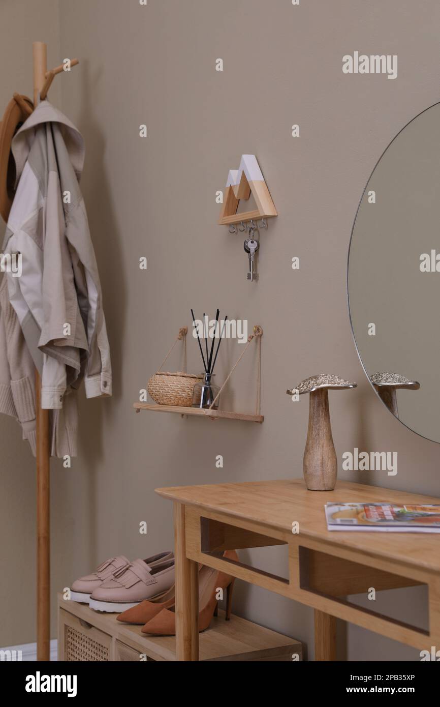 Modern hallway interior with stylish furniture, table and wooden hanger ...