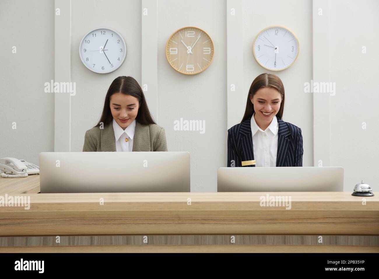 Beautiful receptionists working at counter in hotel Stock Photo - Alamy