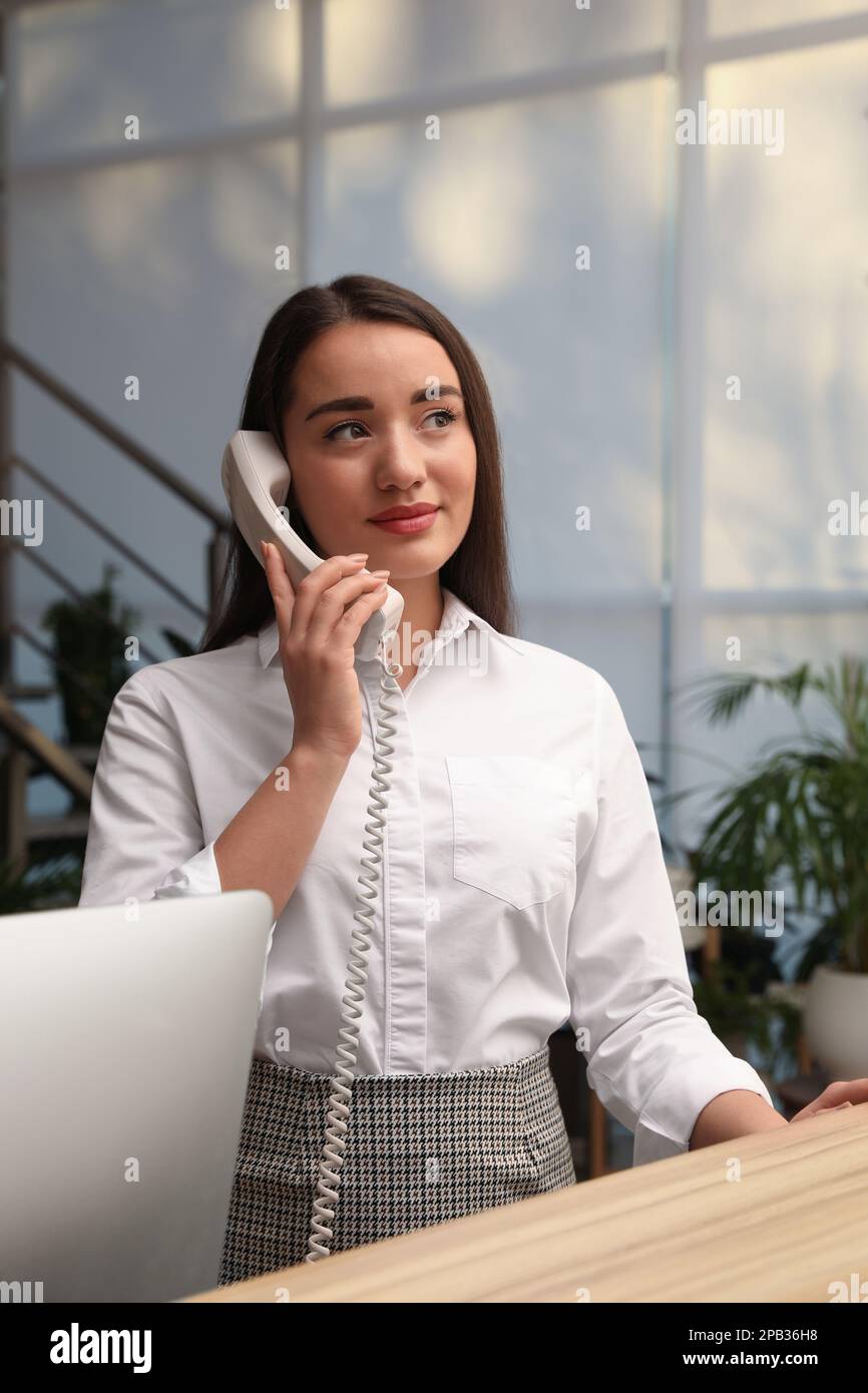 Female receptionist talking on phone at workplace Stock Photo - Alamy
