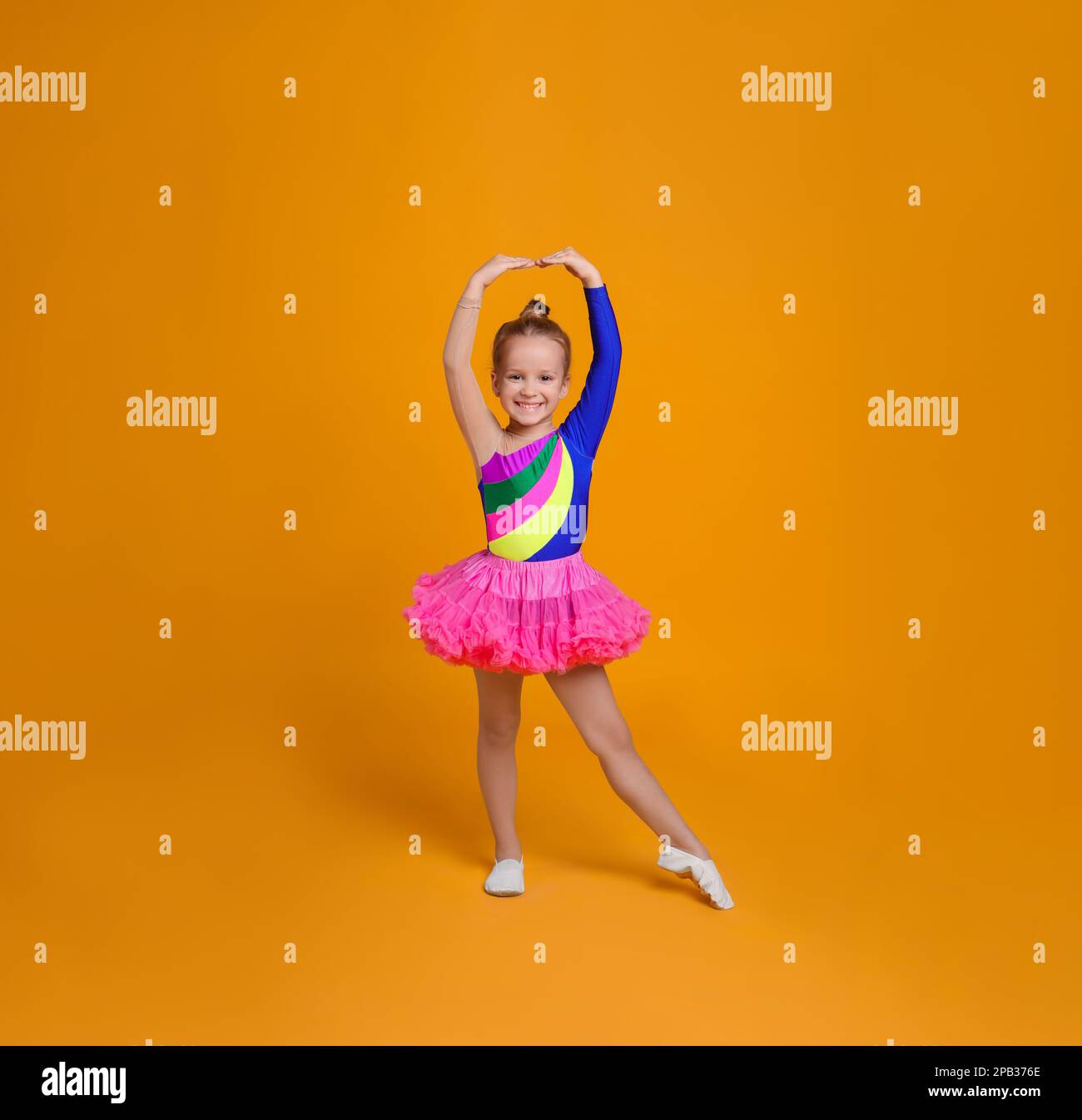 Cute little girl in costume dancing on orange background Stock Photo ...