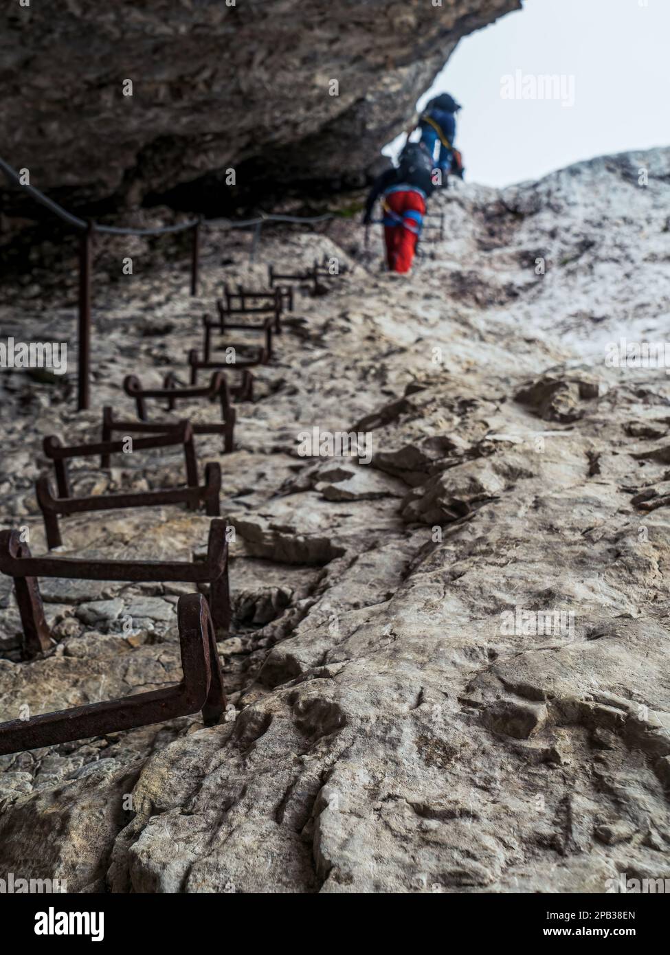 Two mountain climbers going up on a via ferrata ladder route, selective ...