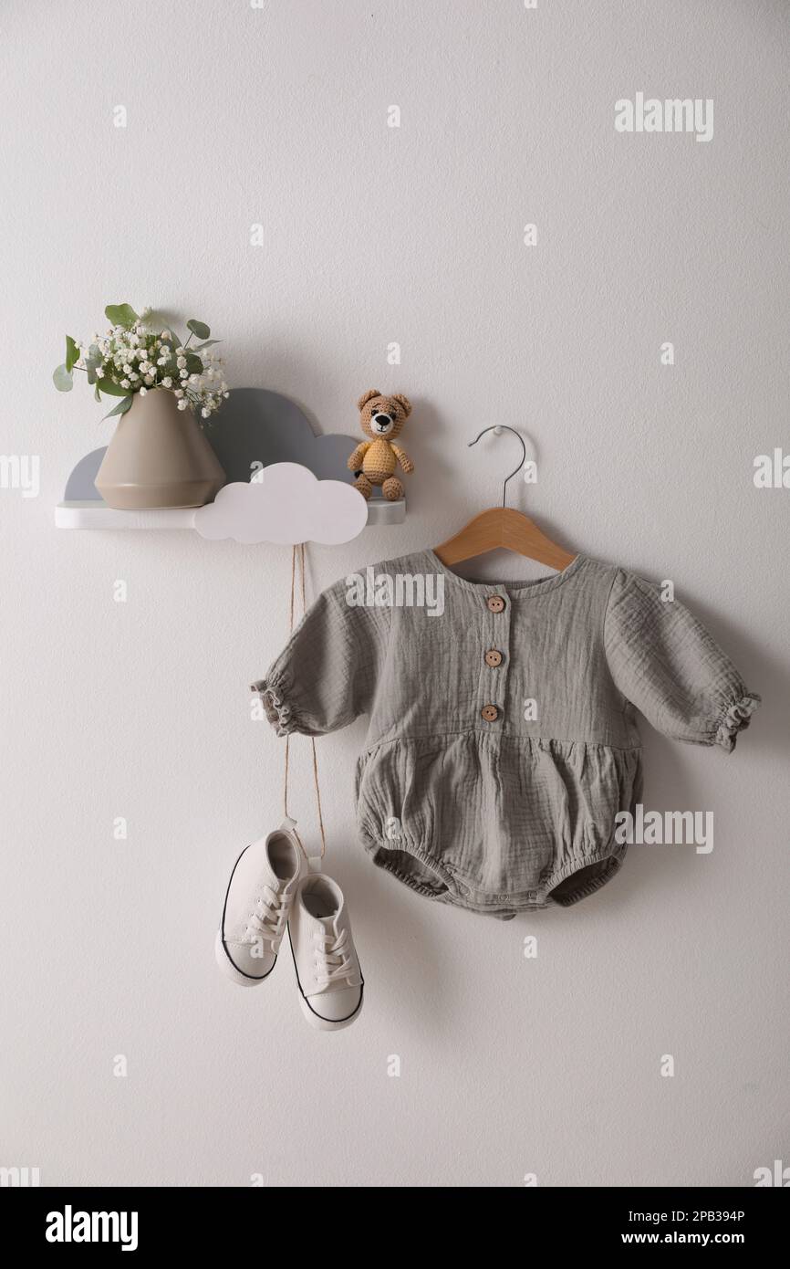 Cute baby onesie and shoes hanging on white wall Stock Photo - Alamy