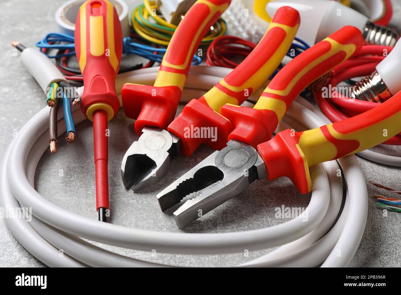 Set of electrician's tools and accessories on grey background, closeup ...
