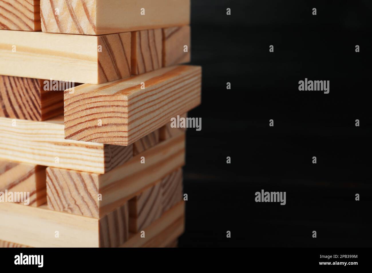Jenga tower made of wooden blocks on black background, closeup. Space ...