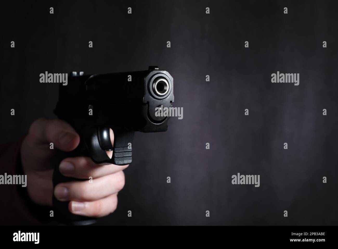 Man aiming gun against dark background, closeup. Space for text Stock ...