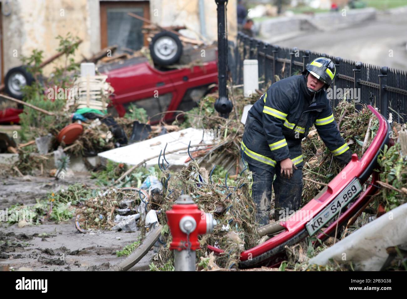 A Slovenian firefighter clears the parts of a car wrecked after floods ...
