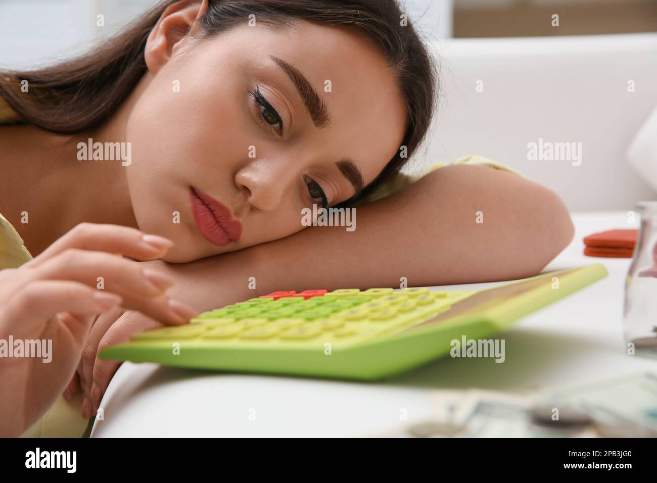 Sad woman counting money with calculator on sofa indoors Stock Photo ...