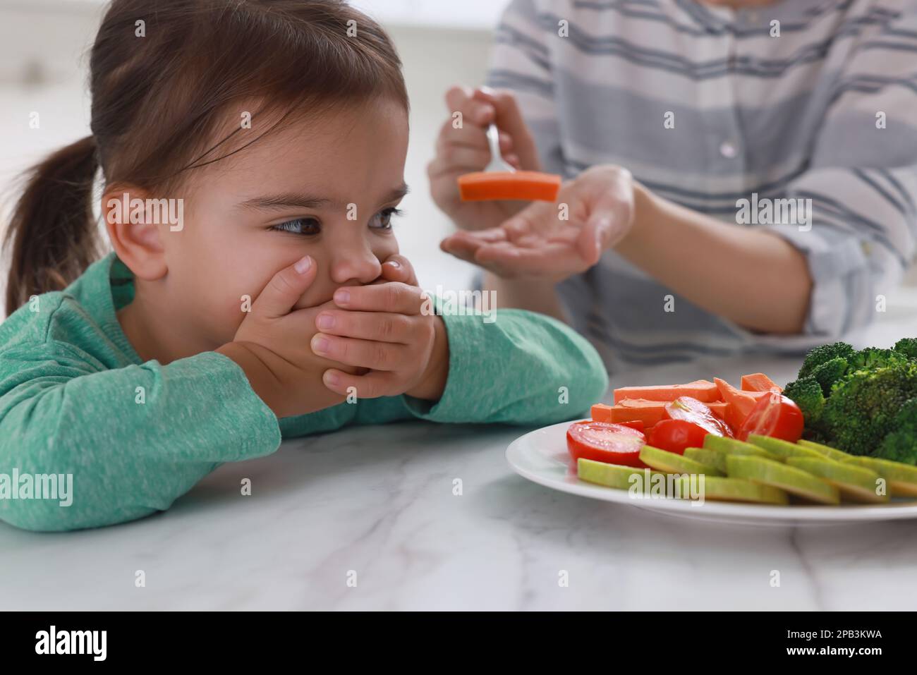 Mother feeding her daughter indoors, closeup. Little girl refusing to ...