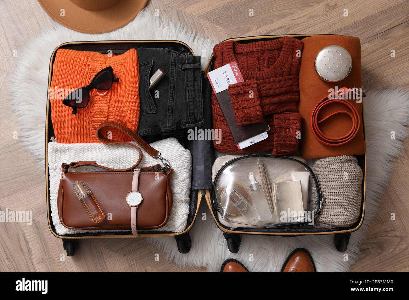 Open suitcase with folded clothes and accessories on floor, flat lay ...