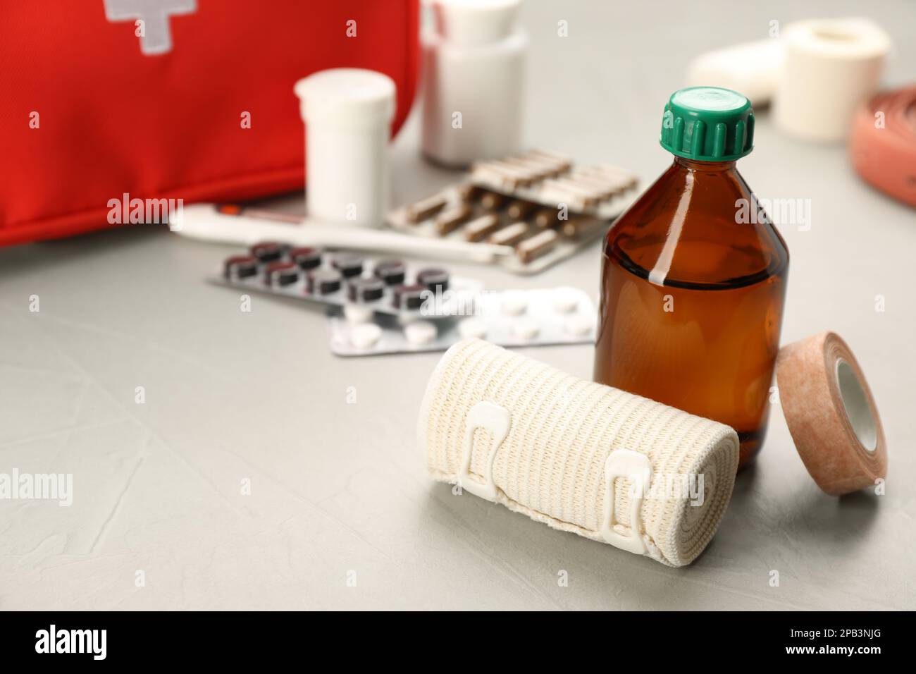 Bandage, sticking plaster roll and medical alcohol on grey table, space ...