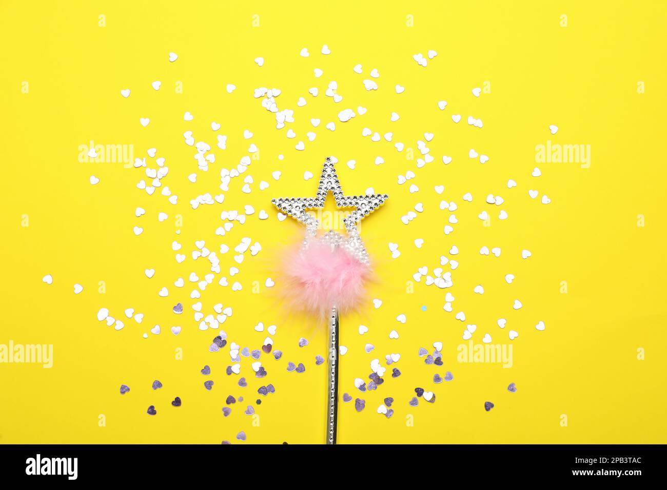 Beautiful silver magic wand with feather and confetti on yellow ...