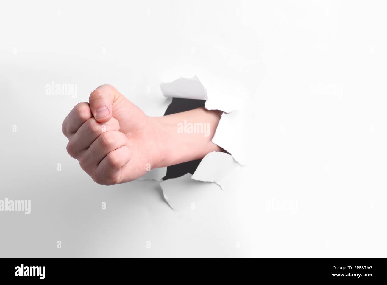 Man breaking through white paper with fist, closeup. Space for text ...
