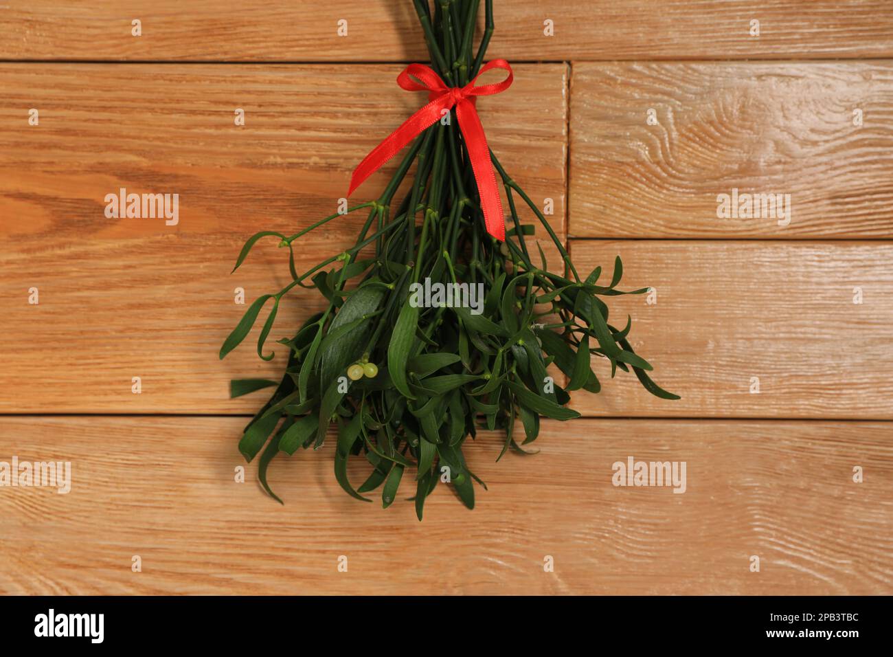 Mistletoe bunch with red bow on wooden table, top view. Traditional ...