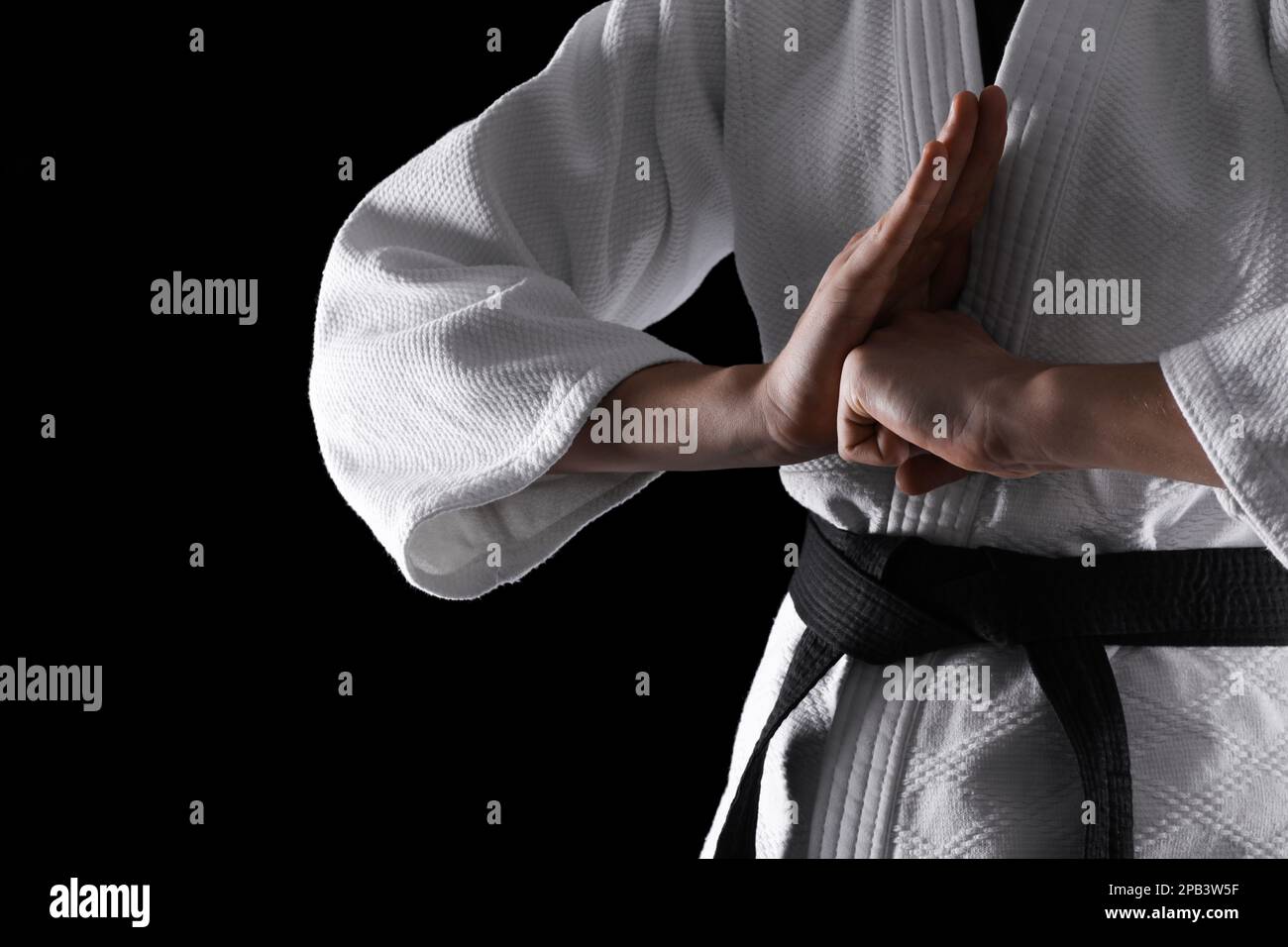 Man in keikogi with black belt on dark background, closeup. Martial ...