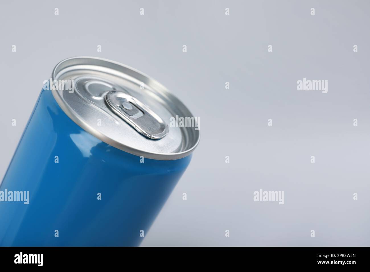 Blue can of energy drink on light grey background, closeup. Space for ...