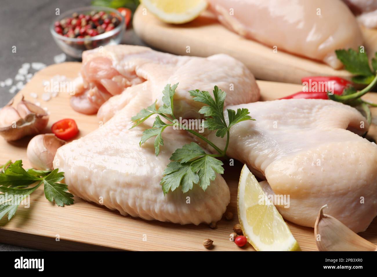 Fresh raw chicken wings and other products on wooden board, closeup ...
