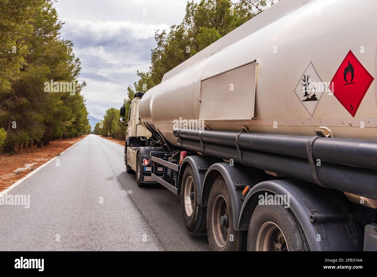 Fuel tanker truck circulating on a narrow and straight road through a ...