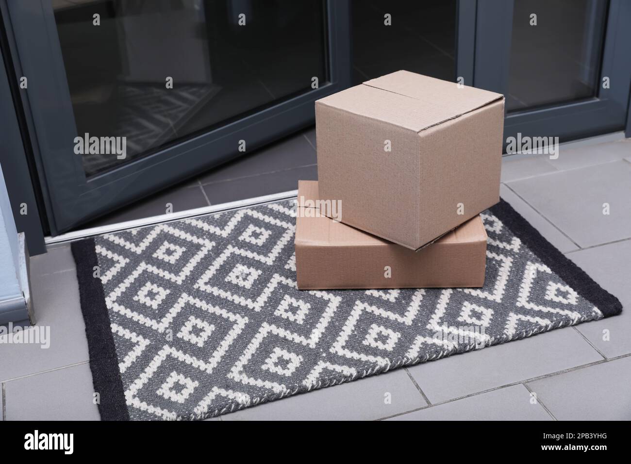 Cardboard boxes on stylish door mat near entrance Stock Photo - Alamy