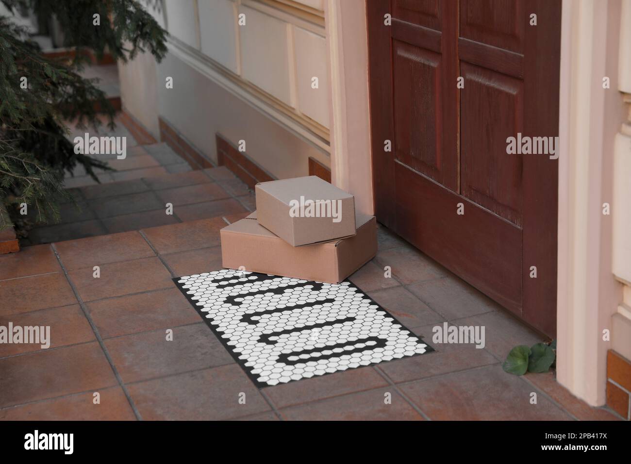 Cardboard boxes on stylish door mat near entrance Stock Photo - Alamy