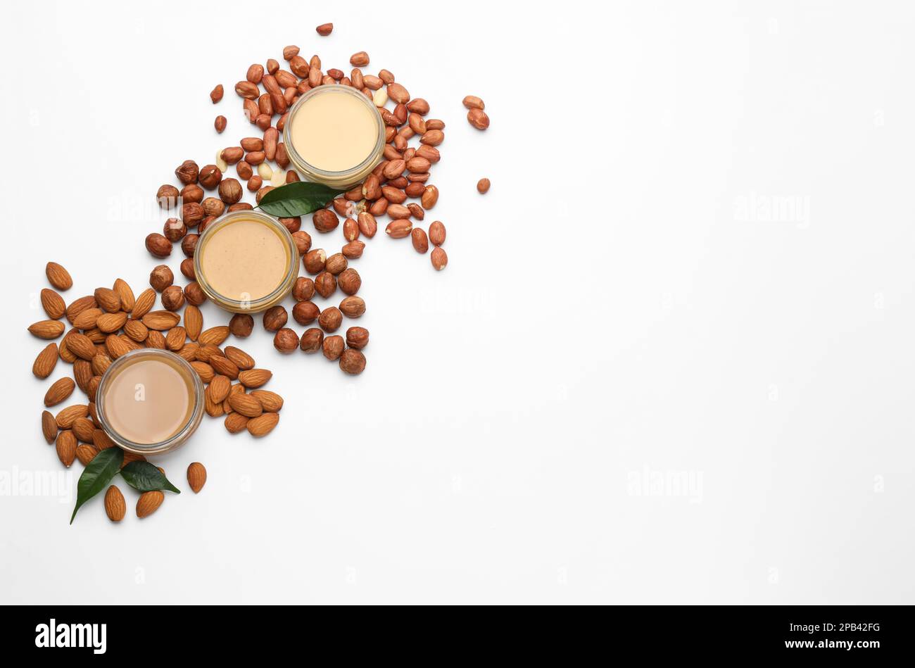 Different types of delicious nut butters and ingredients on white ...