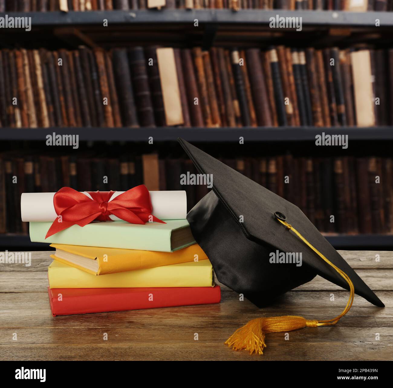 Graduation hat, books and diploma on wooden table in library Stock ...