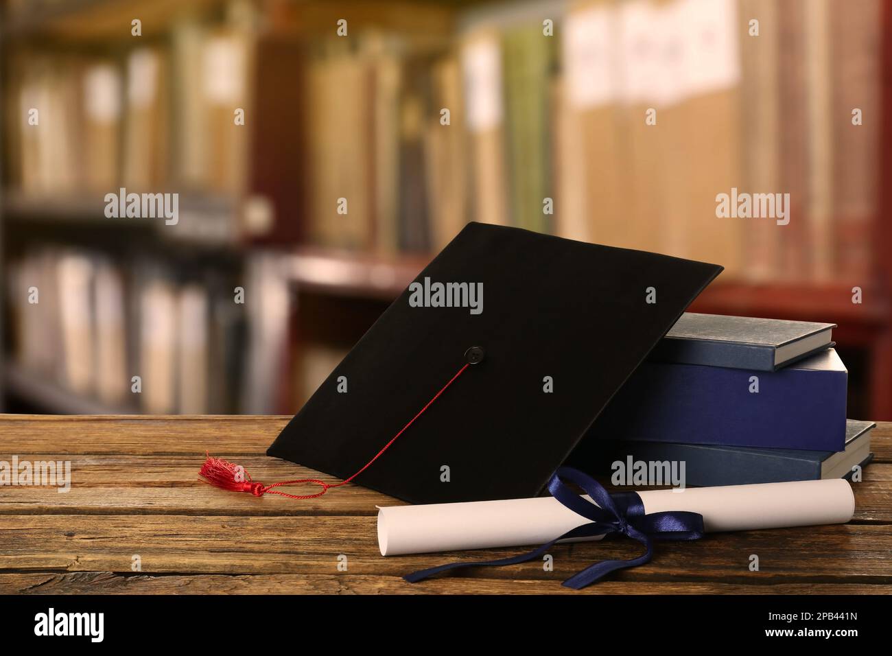Graduation hat, books and diploma on wooden table in library Stock ...