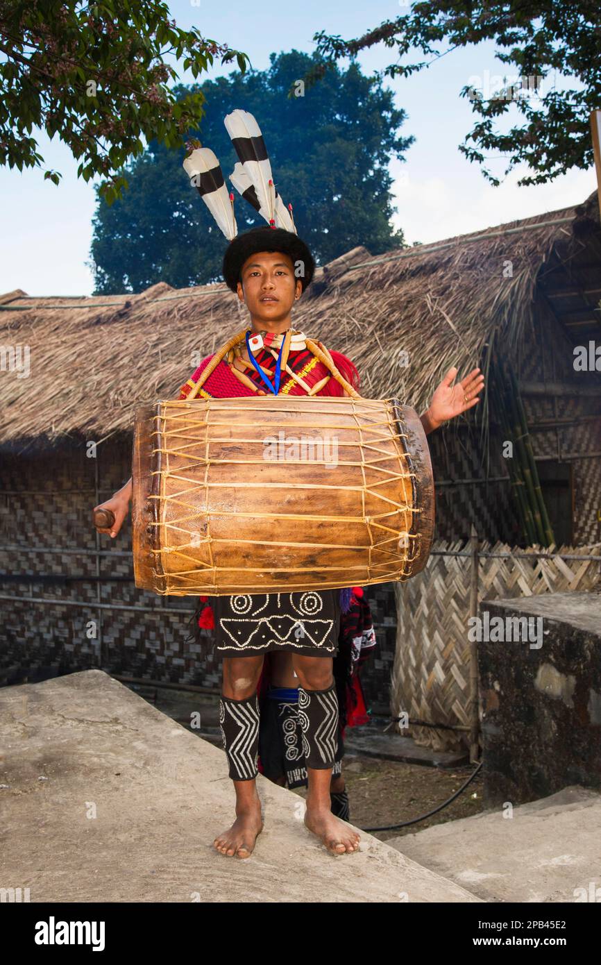 Naga tribesman in traditional dress playing drum, Kisima Nagaland ...