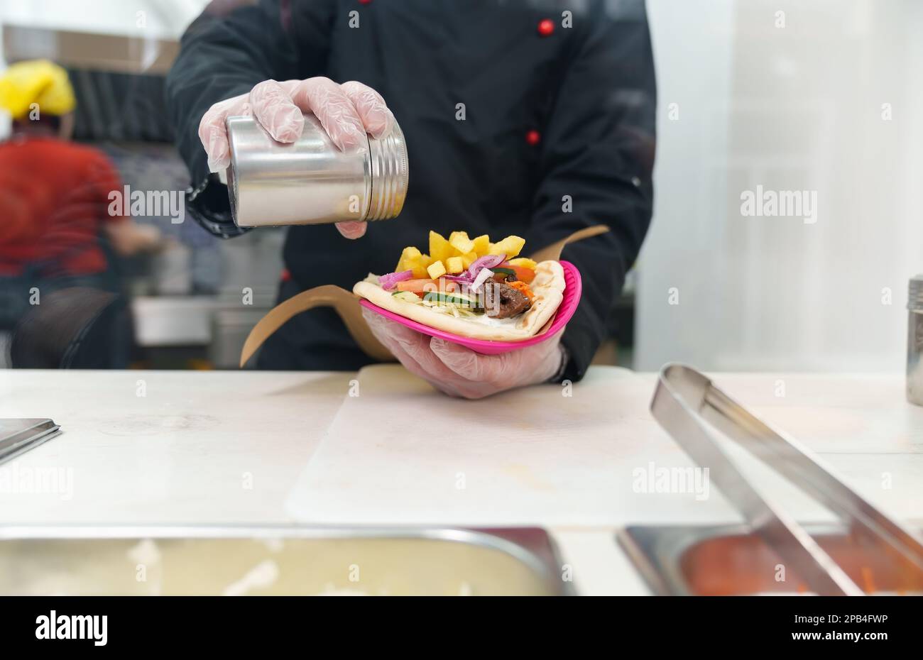 Cook pouring salt on souvlaki in kitchen. Chef cooking traditional ...