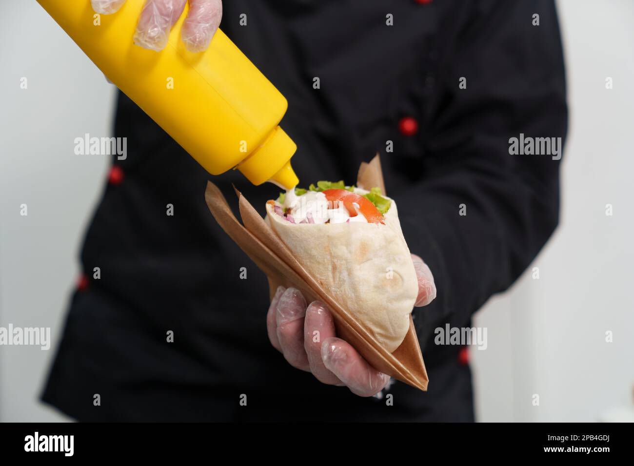 Chef cook pouring white tzatziki sauce on pita crete snack in fast food ...