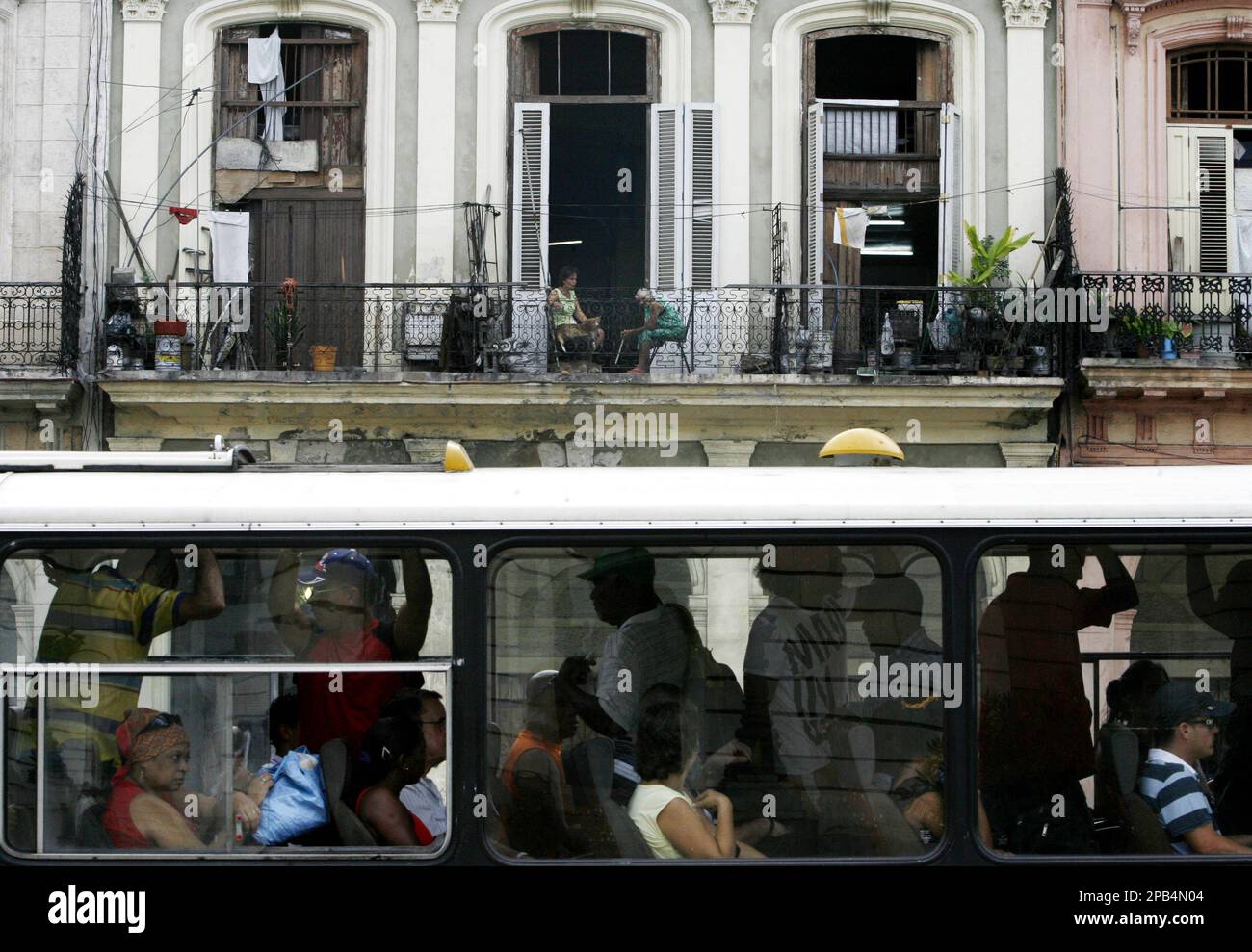 Cuban are seen through the window of a public bus as two women chat in ...