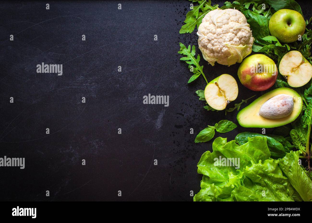 Fresh green vegetables and fruits on black chalk board background ...