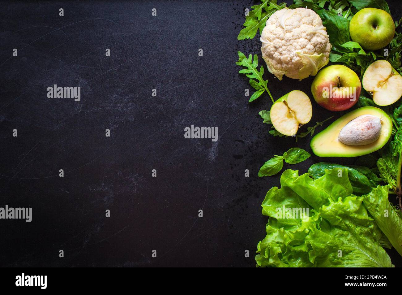 Fresh green vegetables and fruits on black chalk board background ...