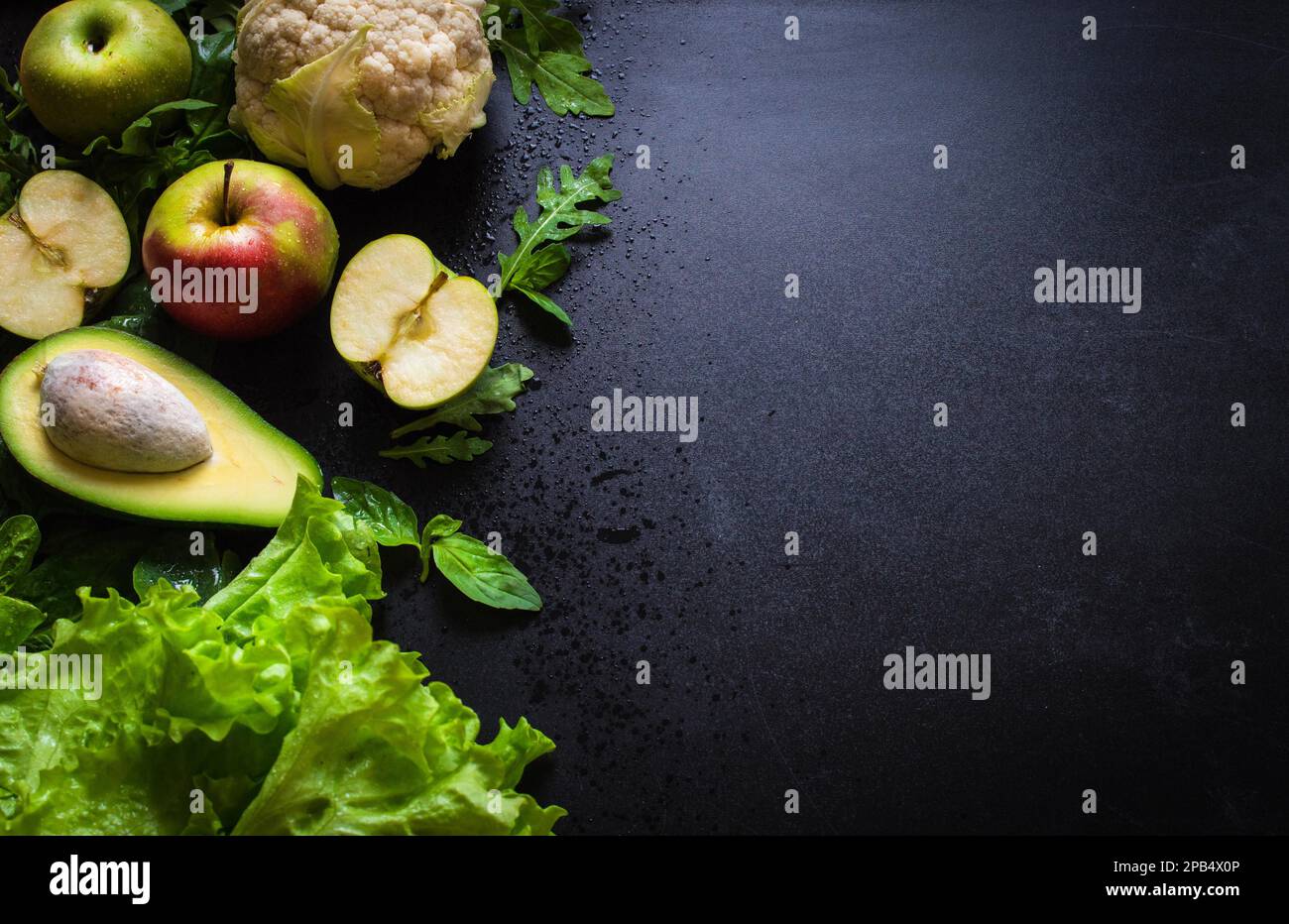 Fresh green vegetables and fruits on black chalk board background ...