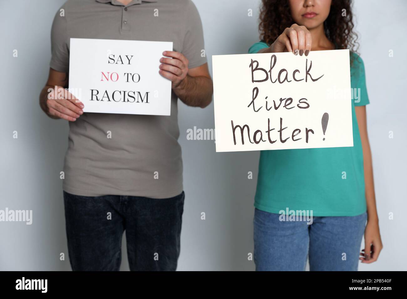 Man and African American woman holding signs on grey background ...