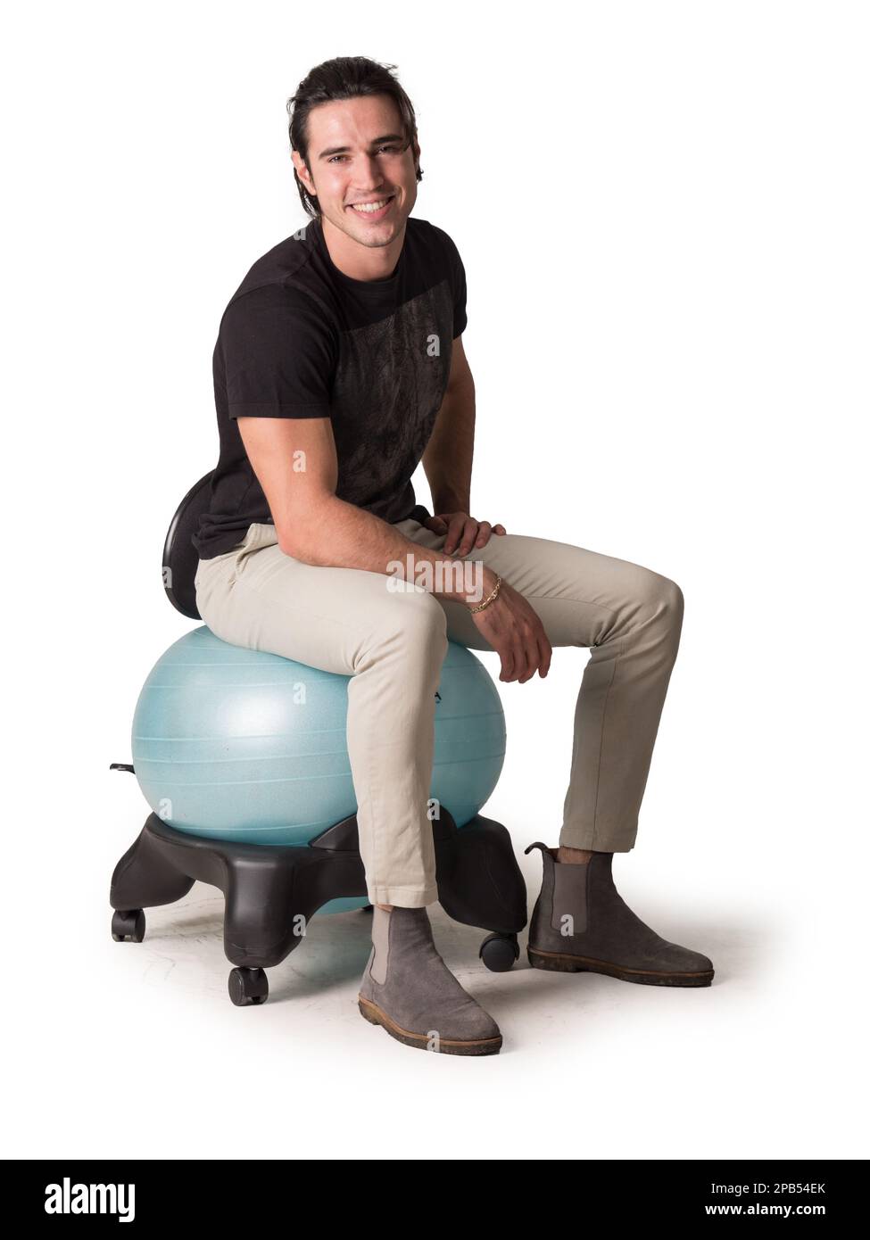 Man sitting on balance ball chair against white background Stock Photo ...