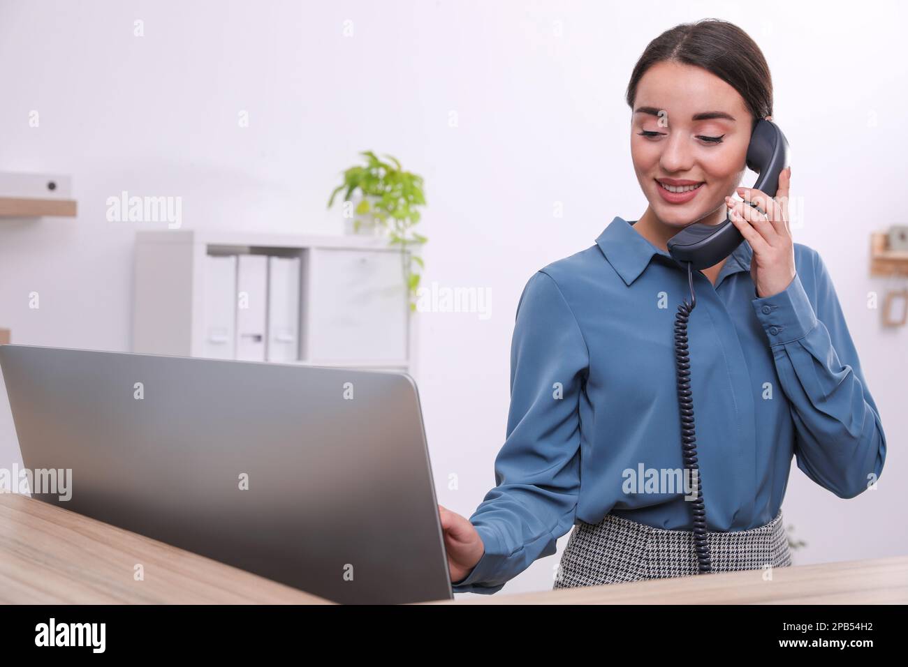 Female receptionist talking on phone at workplace Stock Photo - Alamy