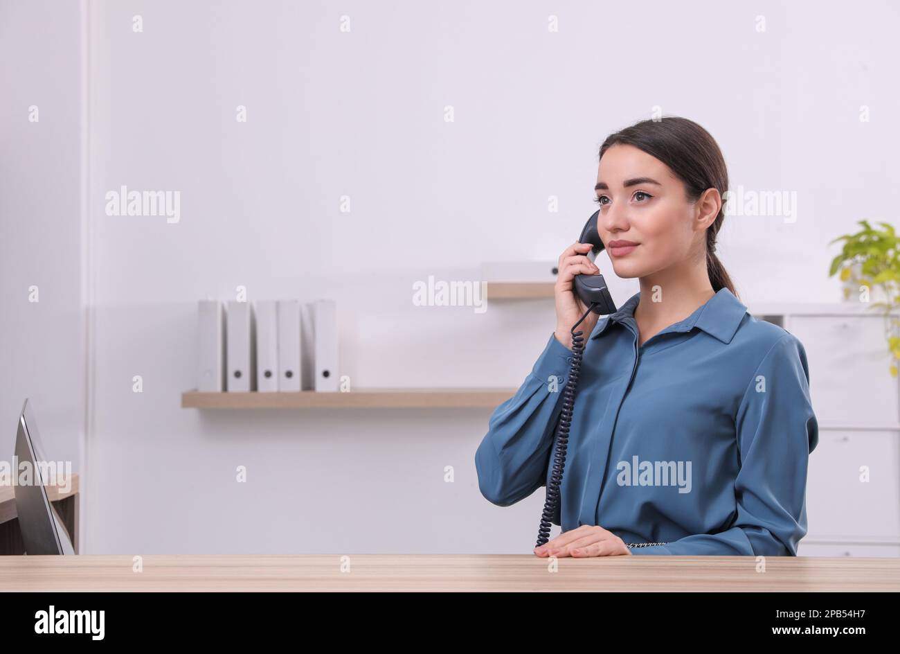 Female receptionist talking on phone at workplace. Space for text Stock ...