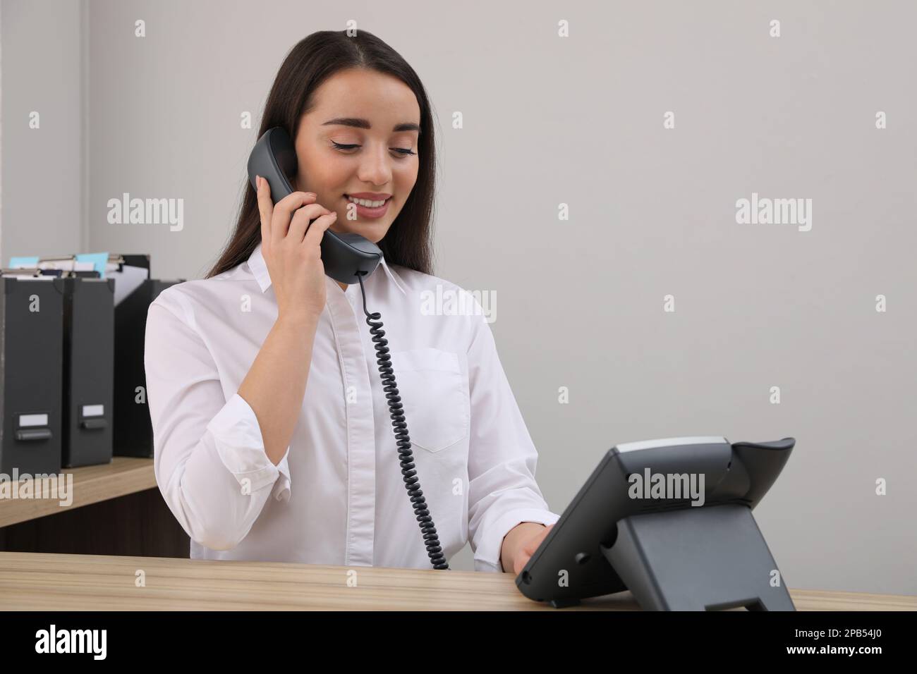 Female receptionist talking on phone at workplace Stock Photo - Alamy