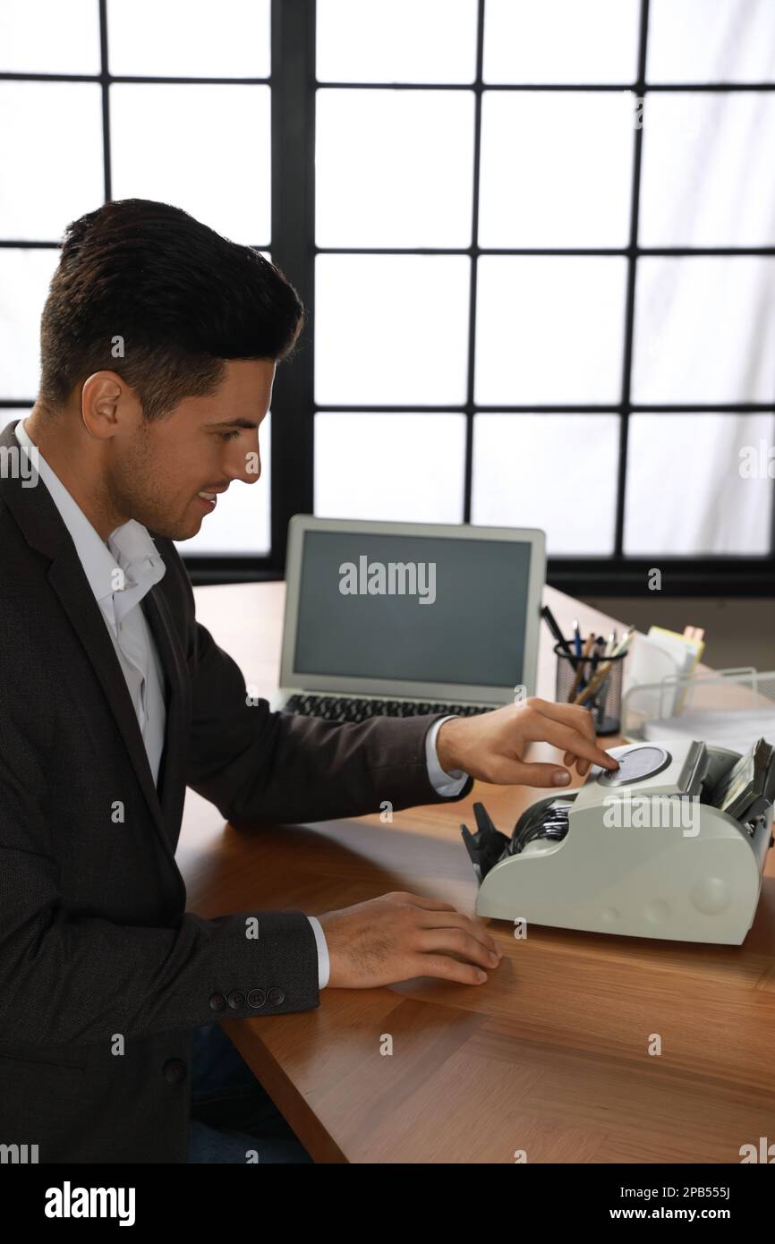 Man using banknote counter at wooden table indoors Stock Photo - Alamy