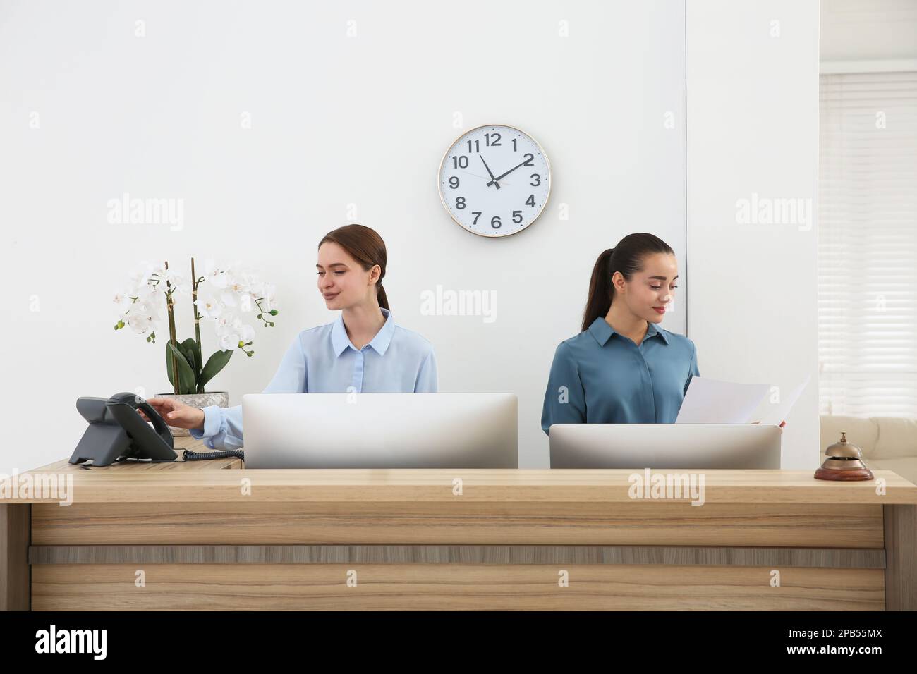 Beautiful receptionists working at counter in hotel Stock Photo - Alamy