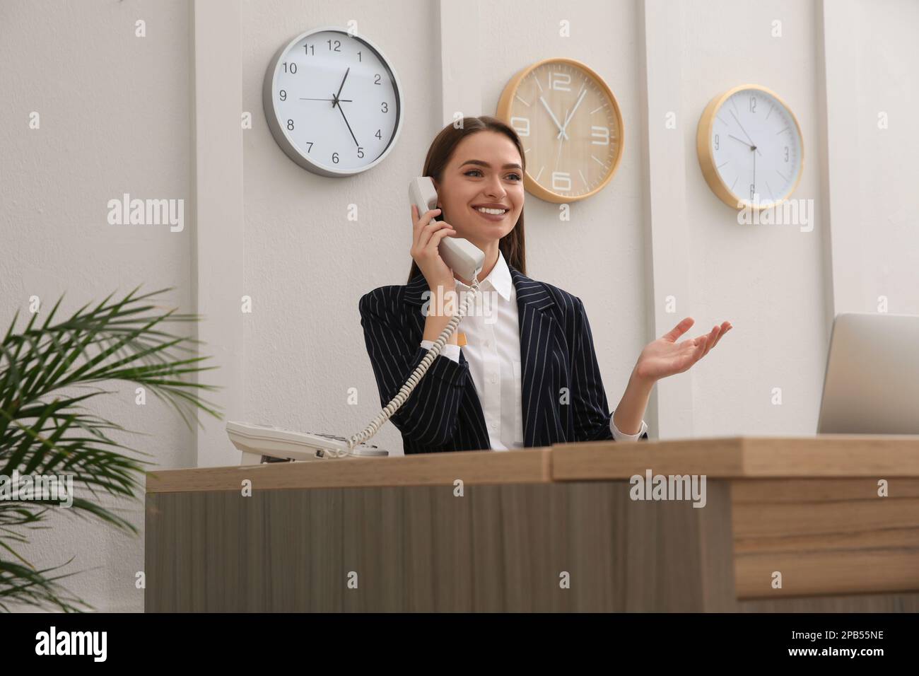 Beautiful receptionist talking on phone at counter in hotel Stock Photo ...