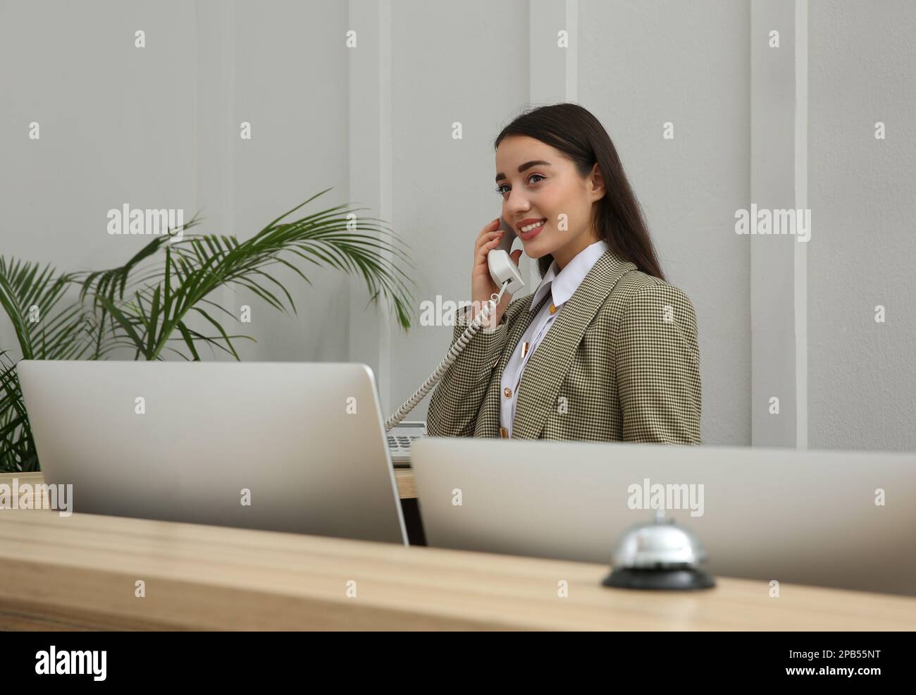 Beautiful receptionist talking on phone at counter in hotel Stock Photo ...