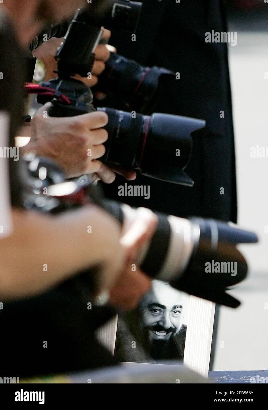 Photographers hold their camera near a picture of late Italian tenor ...