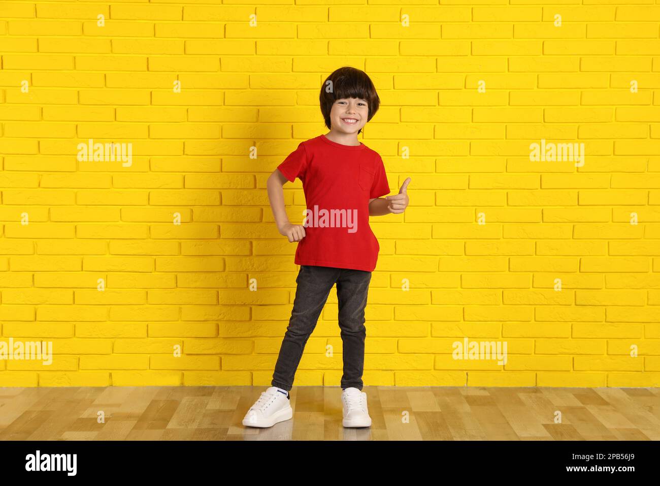Cute little boy near yellow brick wall indoors Stock Photo - Alamy