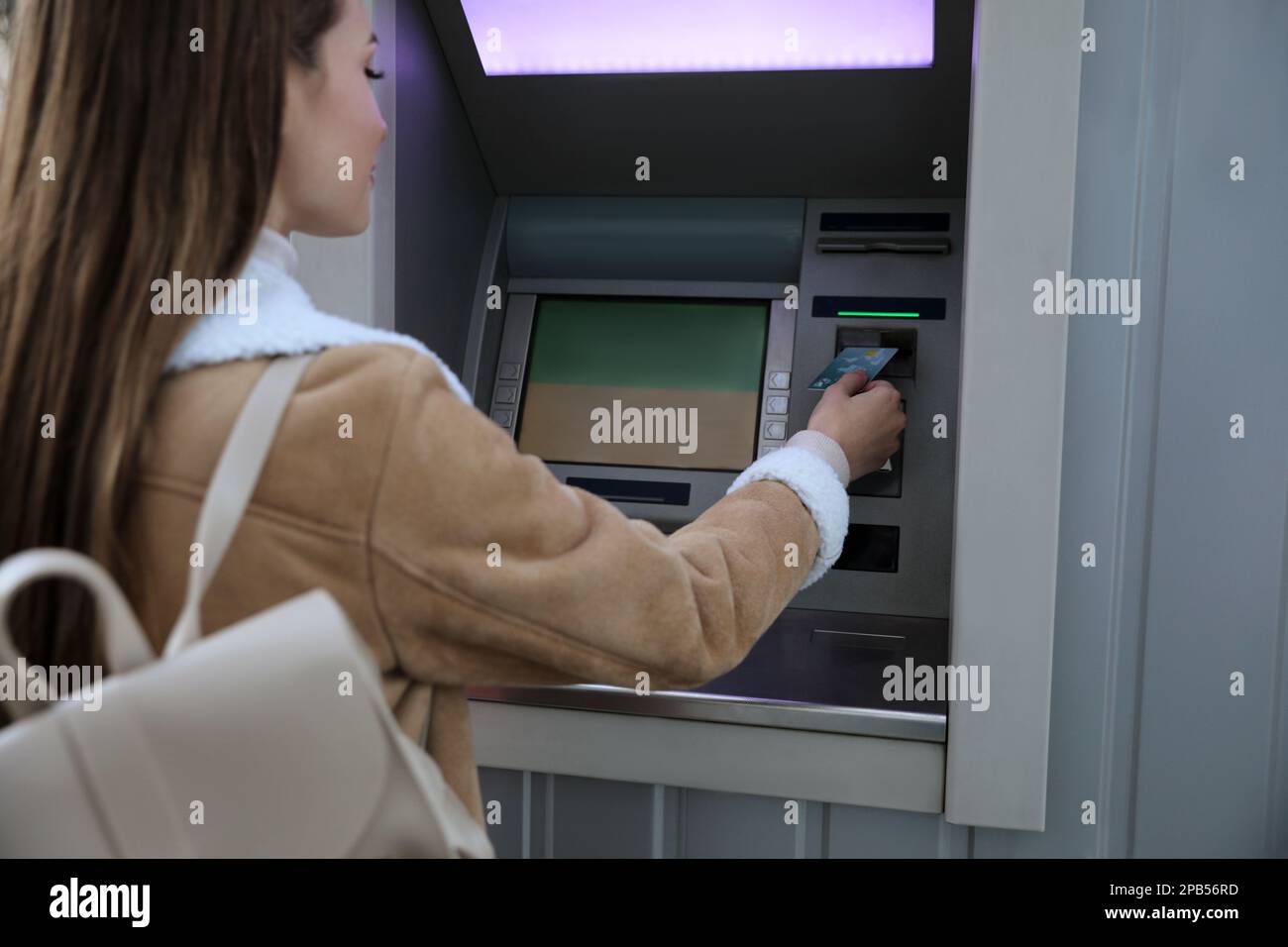 Young woman using cash machine for money withdrawal outdoors, focus on ...